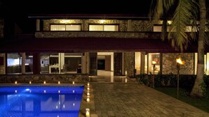 Uma casa moderna com piscina, paredes de pedra e um espaço de estar no pátio com velas.