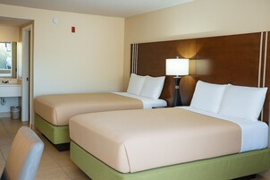 Quarto de hotel com duas camas, uma mesa e uma cadeira.