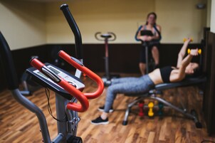 Uma academia com equipamentos de ginástica e uma pessoa deitada em um banco.