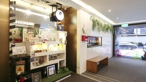 Interior moderno com uma mesa de recepç ão, exposição de diversos objetos e vista para o exterior.