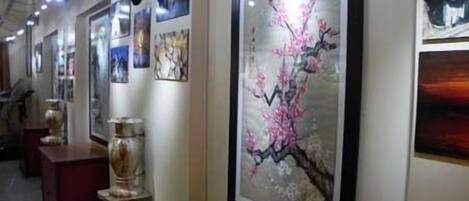 Uma galeria com obras de arte emolduradas nas paredes, incluindo uma peça em destaque de um galho de árvore rosa.