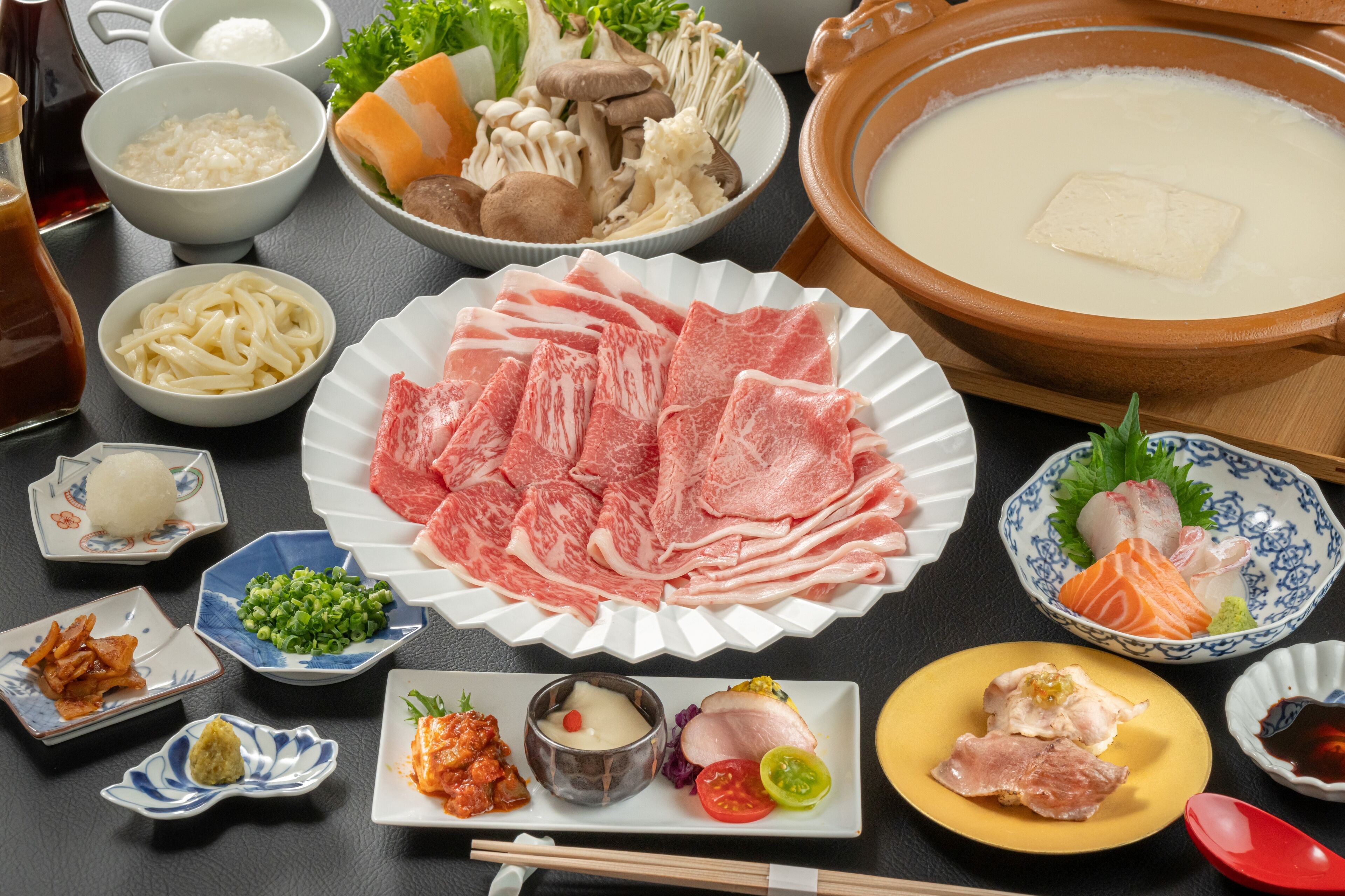 Diversos pratos japoneses, incluindo sashimi, macarrão e um pote quente.