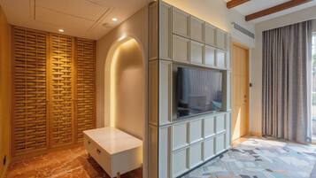Quarto moderno com televisão integrada, um banco e piso estampado.