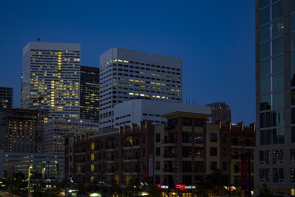 Paisagem urbana ao entardecer com edifícios modernos e arranha-céus com janelas iluminadas.
