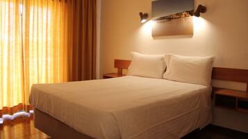 Cama bem arrumada com lençóis brancos em um quarto de hotel.