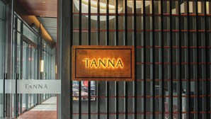 Entrada com a marca Tanna, design moderno, com portão de metal e uma placa.