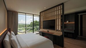 Quarto de hotel moderno com uma cama grande, uma televisão fixada em um painel de madeira e uma varanda com vista panorâmica.