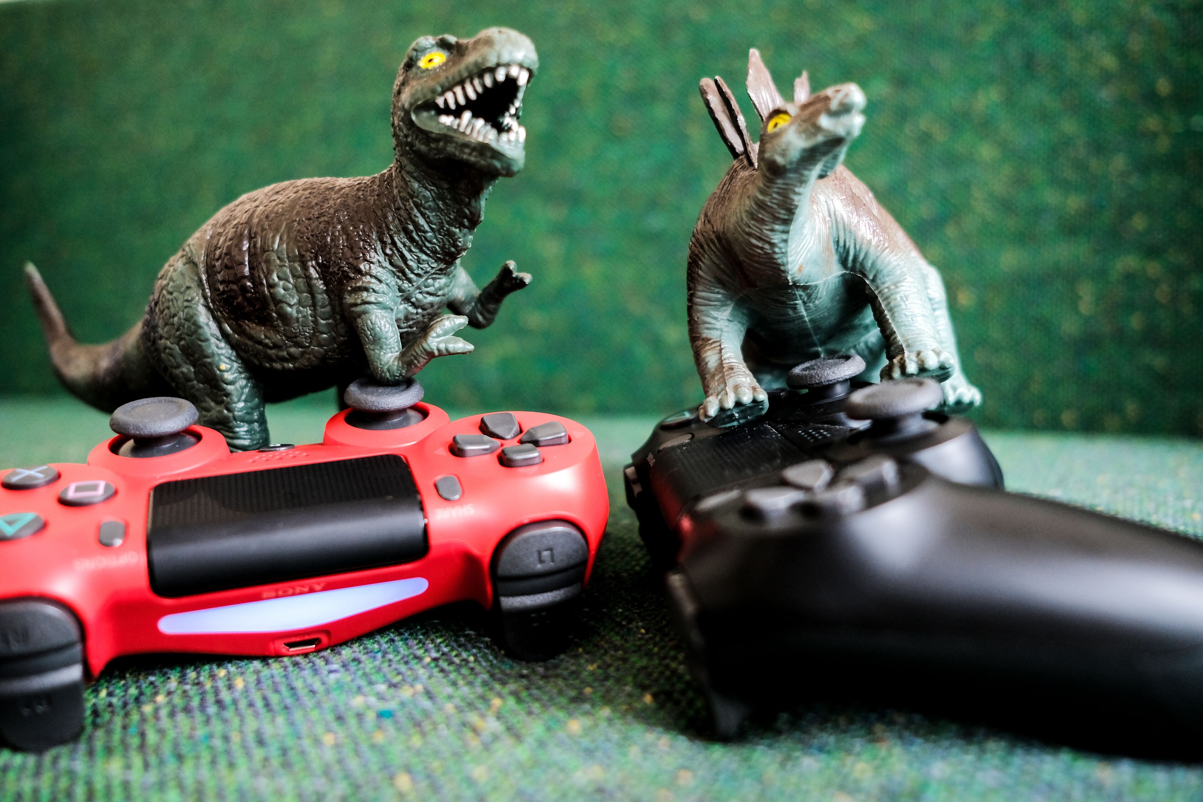 Duas figuras de dinossauros em controles de videogame.