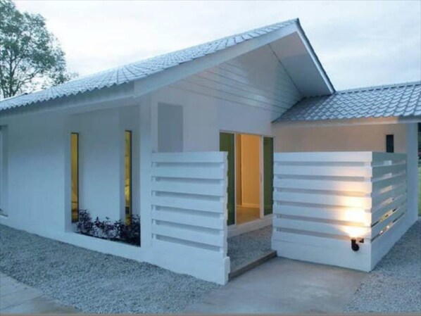 Uma casa moderna com telhado inclinado, paredes externas brancas e um pequeno alpendre.