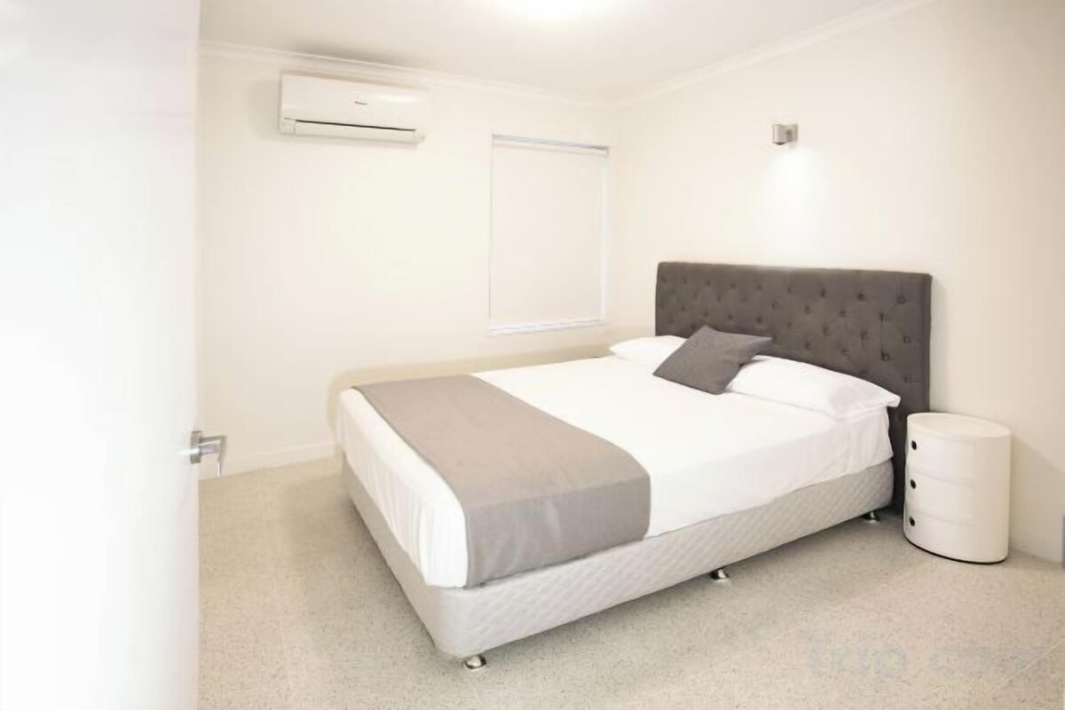 Quarto com cama, mesa de cabeceira e ar condicionado.