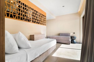 Quarto moderno com cama, sofá e painel decorativo de madeira.