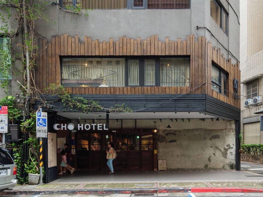 Entrada de hotel com fachada de madeira, uma placa e sinal de vaga para deficientes.