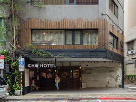 Entrada de hotel com fachada de madeira, uma placa e sinal de vaga para deficientes.
