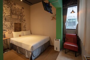 Um quarto com uma cama, uma cadeira vermelha, um projetor e um mural na parede.