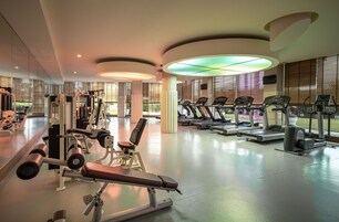 Uma academia moderna com diversos equipamentos de exercício, amplas janelas e um espaço limpo e amplo.