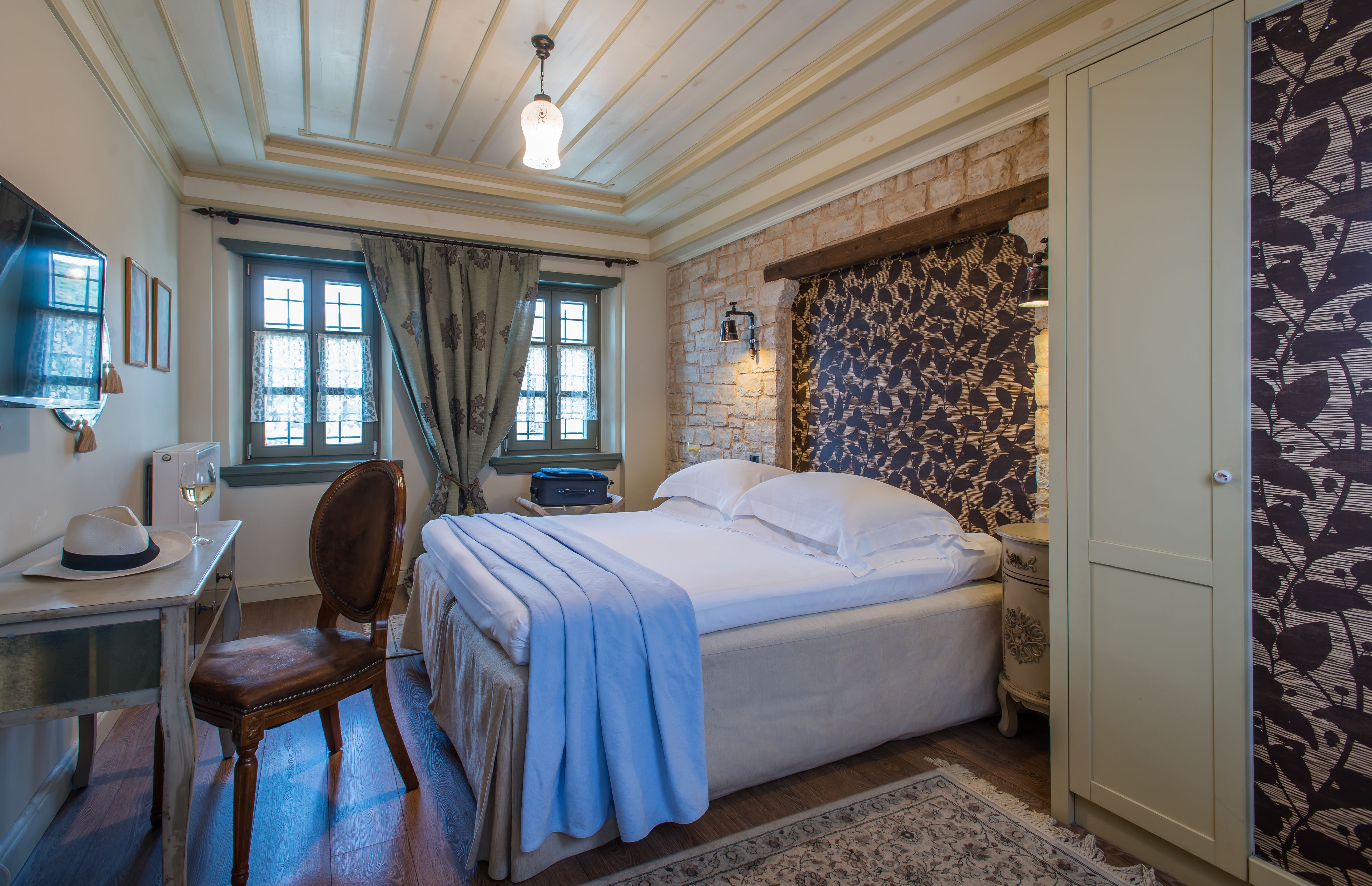 Quarto com cama, escrivaninha, cadeira, mesa de cabeceira e guarda-roupa.