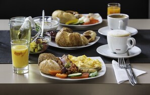 Uma mesa posta para o café da manhã com diversos alimentos e bebidas.