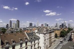 Paisagem urbana com mistura de edifícios históricos e modernos, céu claro e rua larga.