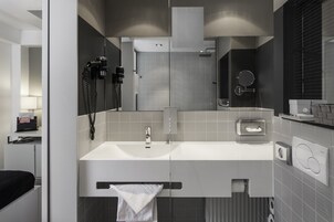 Um banheiro moderno com uma pia grande, um espelho, porta-toalhas e área de chuveiro.