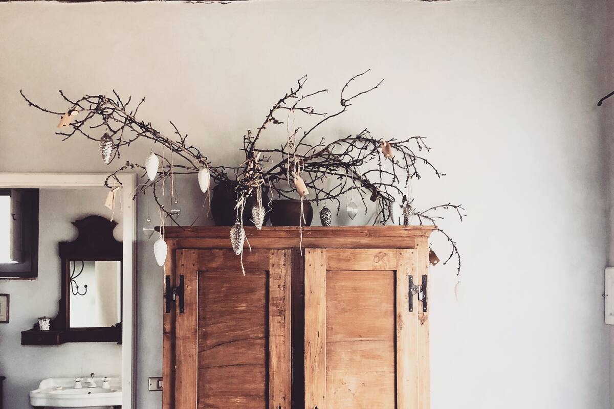 Um armário de madeira com ramos e ornamentos, um espelho e uma pia em um quarto com piso de tijolos.