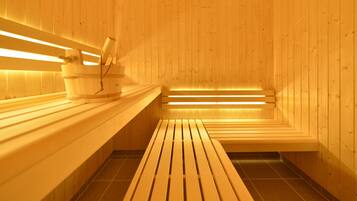 Uma sauna com bancos e corrimãos de madeira, paredes de madeira e um banco com toalha e porta-toalhas.
