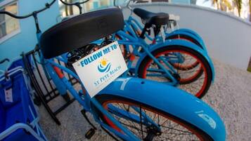 Uma bicicleta azul com uma placa que diz 'Follow Me To St Pete Beach Suites' presa ao selim.