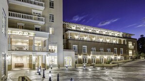 Um hotel com pátio central, várias varandas e uma entrada bem iluminada.