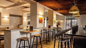 Uma área de bar moderna com banquetas de madeira, parede de destaque em tijolo e iluminação pendente.