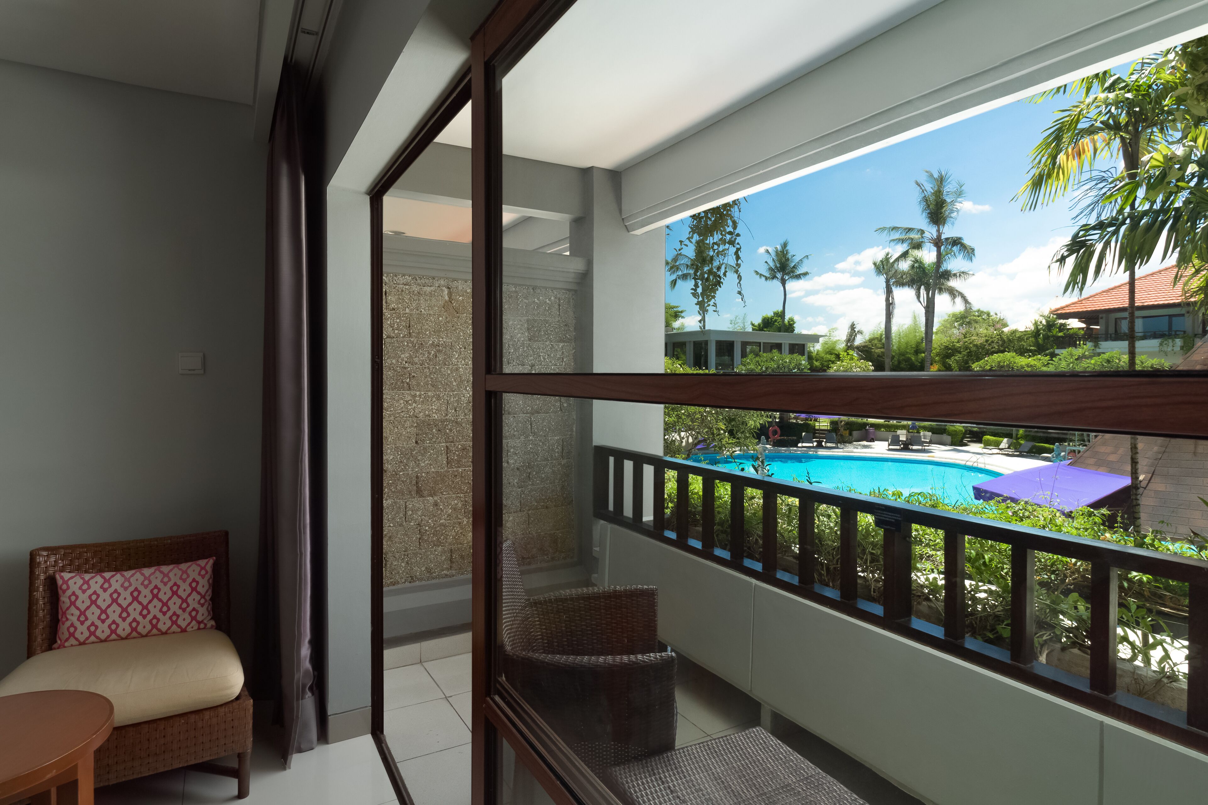 Varanda com vista para uma piscina, mobiliário de vime e uma parede de pedra.