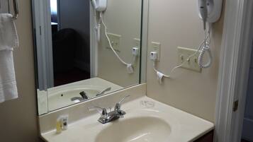 Casa de banho com lavatório, espelho, porta-toalhas e secador de cabelo.