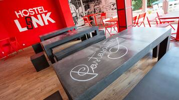 Interior de um hostel com parede vermelha, um mural em estilo de graffiti e uma mesa com a palavra 'Pantsy'.