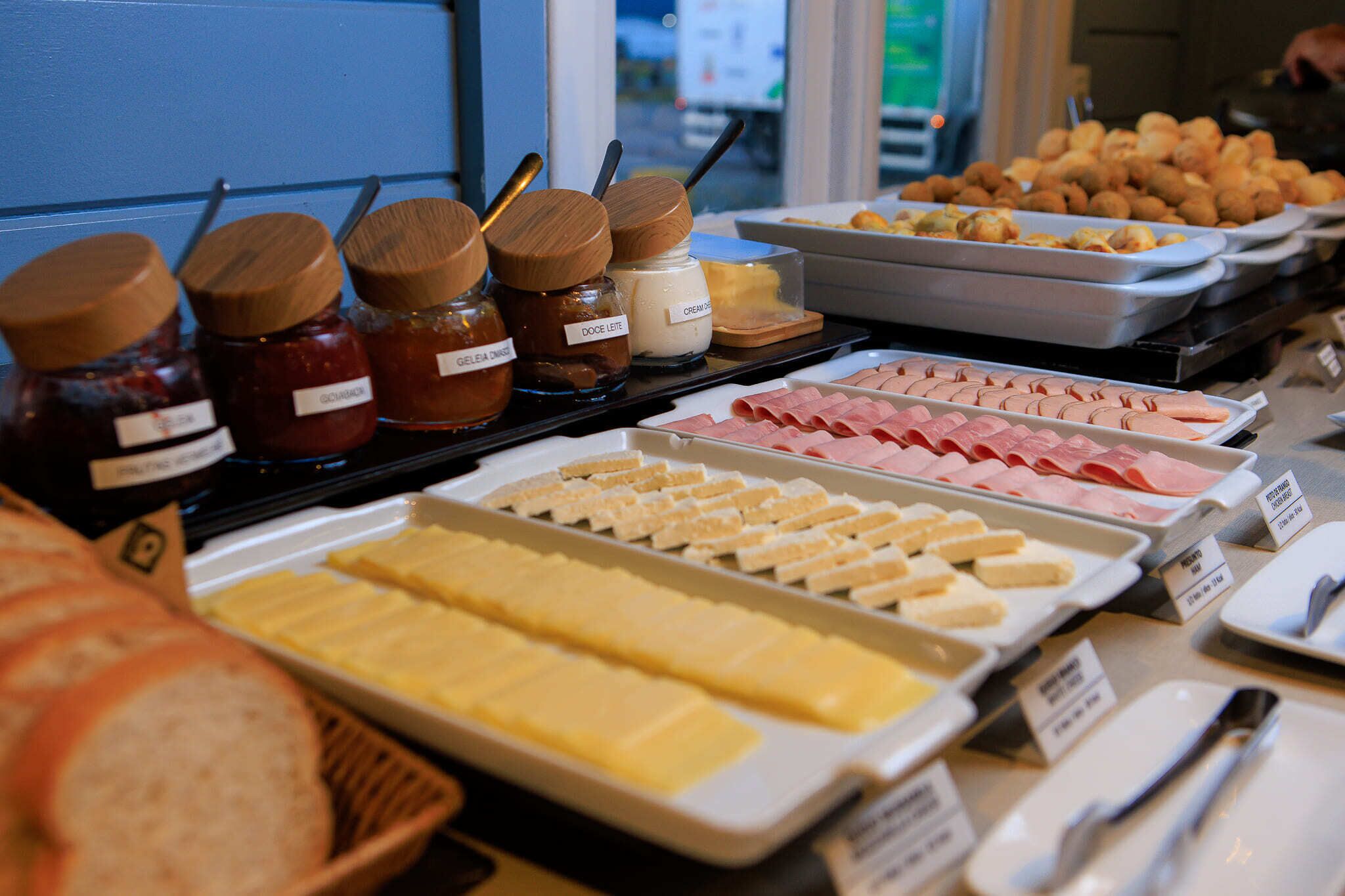 Buffet com diversas opções de comida, incluindo carnes, queijos e acompanhamentos.
