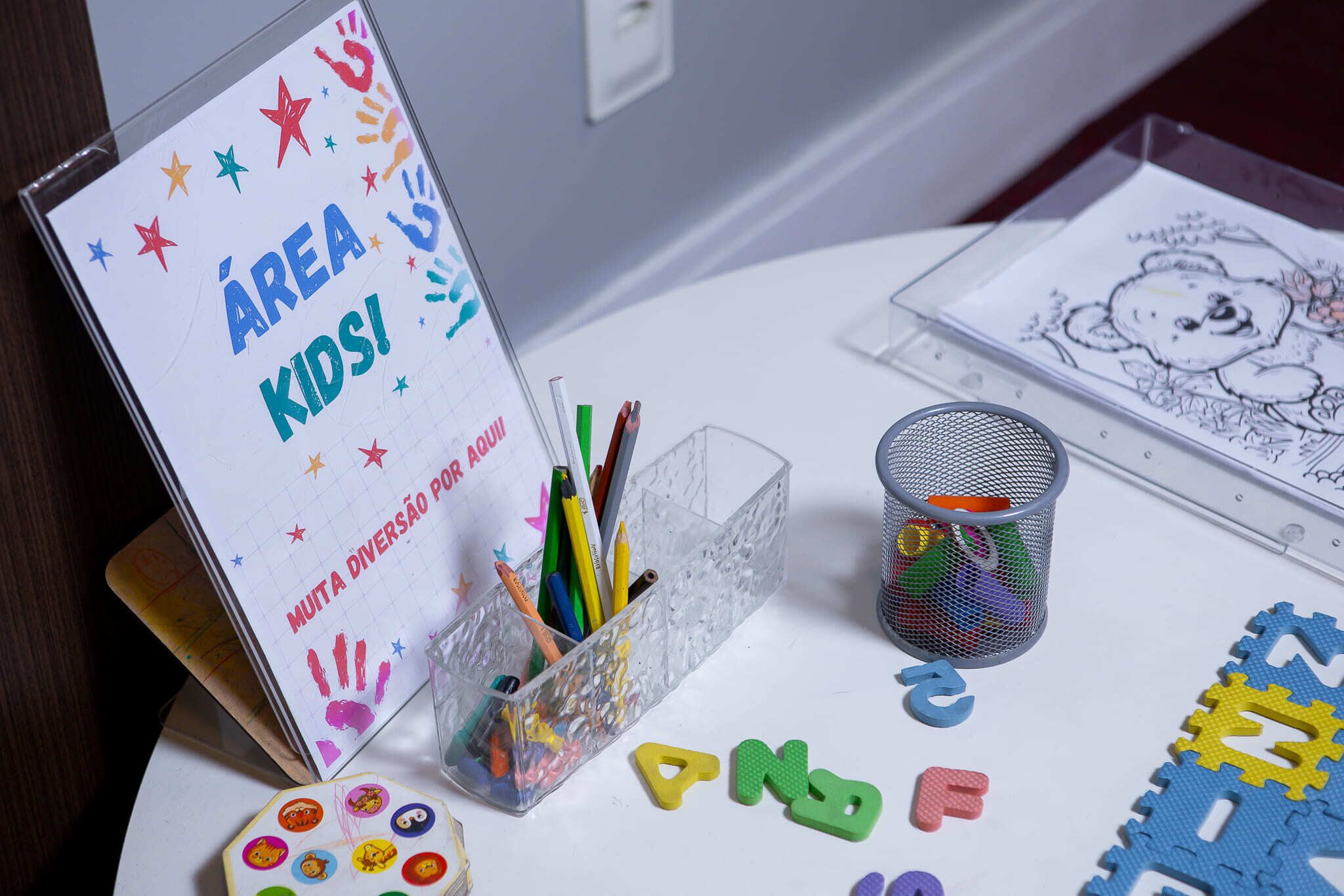 Uma área de recreação infantil com um aviso, porta-lápis, blocos de alfabeto e um tapete para desenho.
