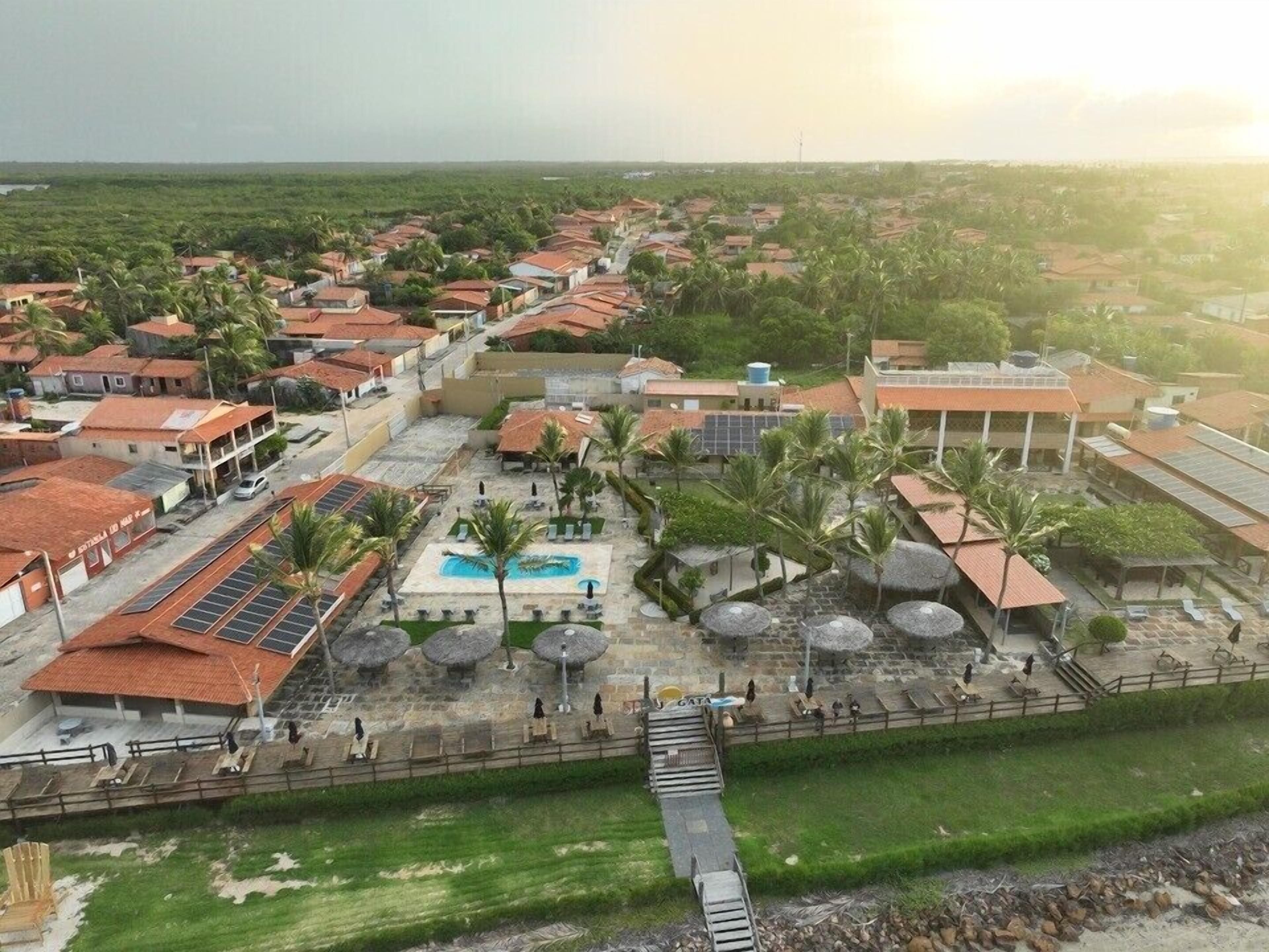 Resort com vários edifícios, piscina e palmeiras.