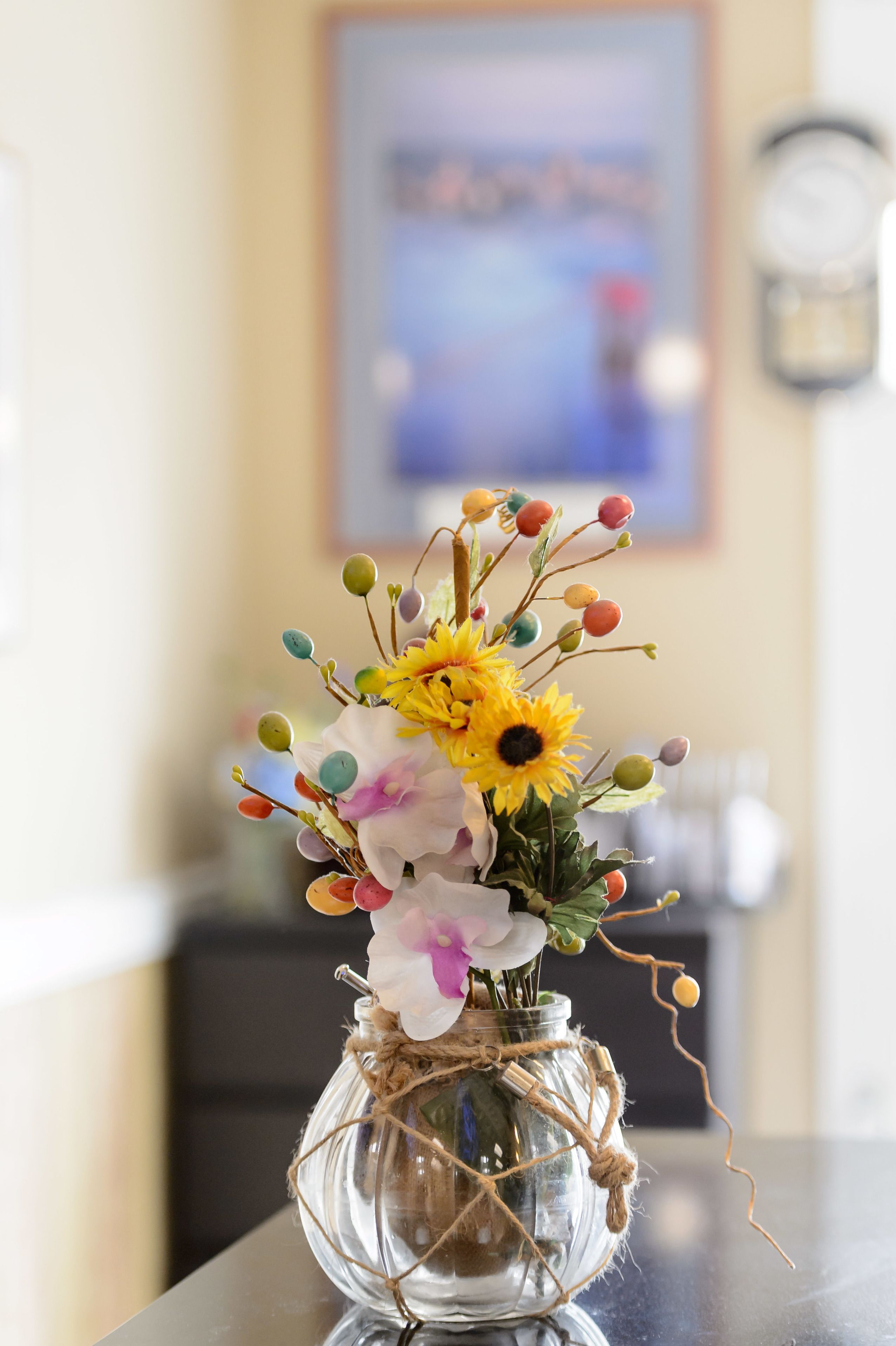 Um vaso de vidro com decoração rústica de corda contendo uma variedade de flores.