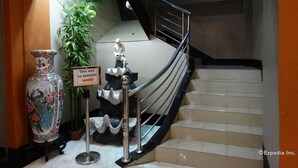 Escada com corrimão de metal, um vaso decorativo e uma placa indicando o caminho para o seminário.