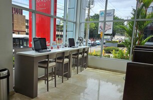 Um espaço de escritório moderno com uma mesa comprida e cadeiras, janelas amplas e vista para a rua.
