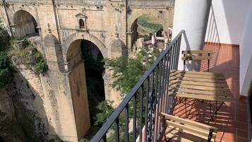Varanda com vista para uma ponte de pedra e vegetação.