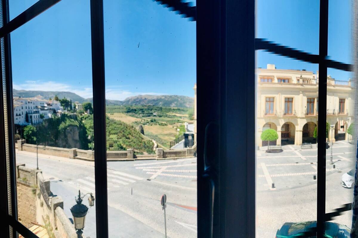 Quarto de hotel com uma janela grande que oferece vista para um edifício e uma rua.