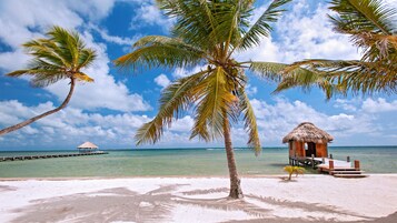 Na praia, praia de areia branca, espreguiçadeiras, guarda-sóis de praia 