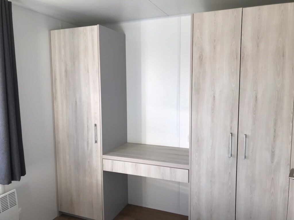 Quarto com secretária embutida e armário.