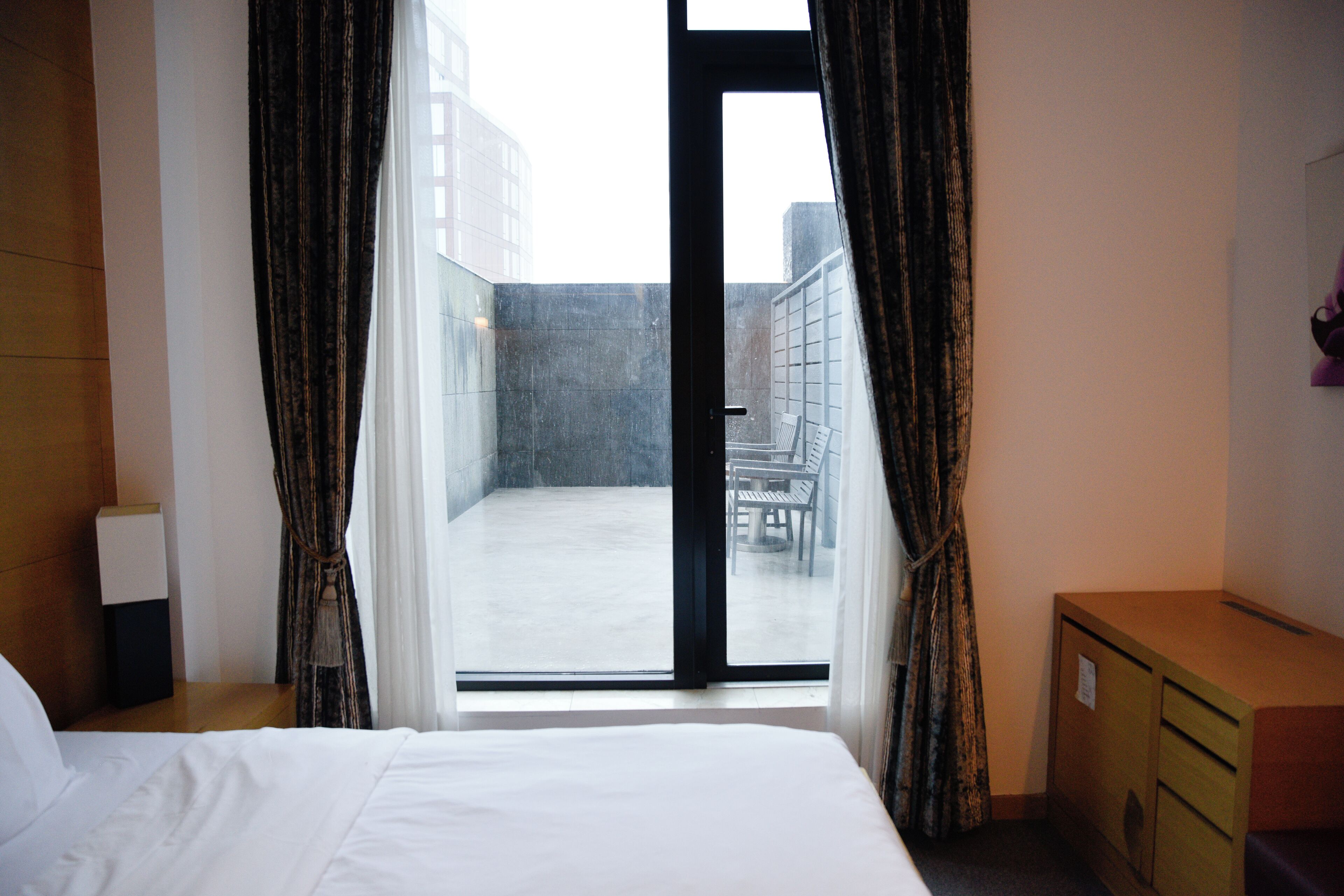 Quarto de hotel com cama, escrivaninha, cadeira e vista para o exterior.