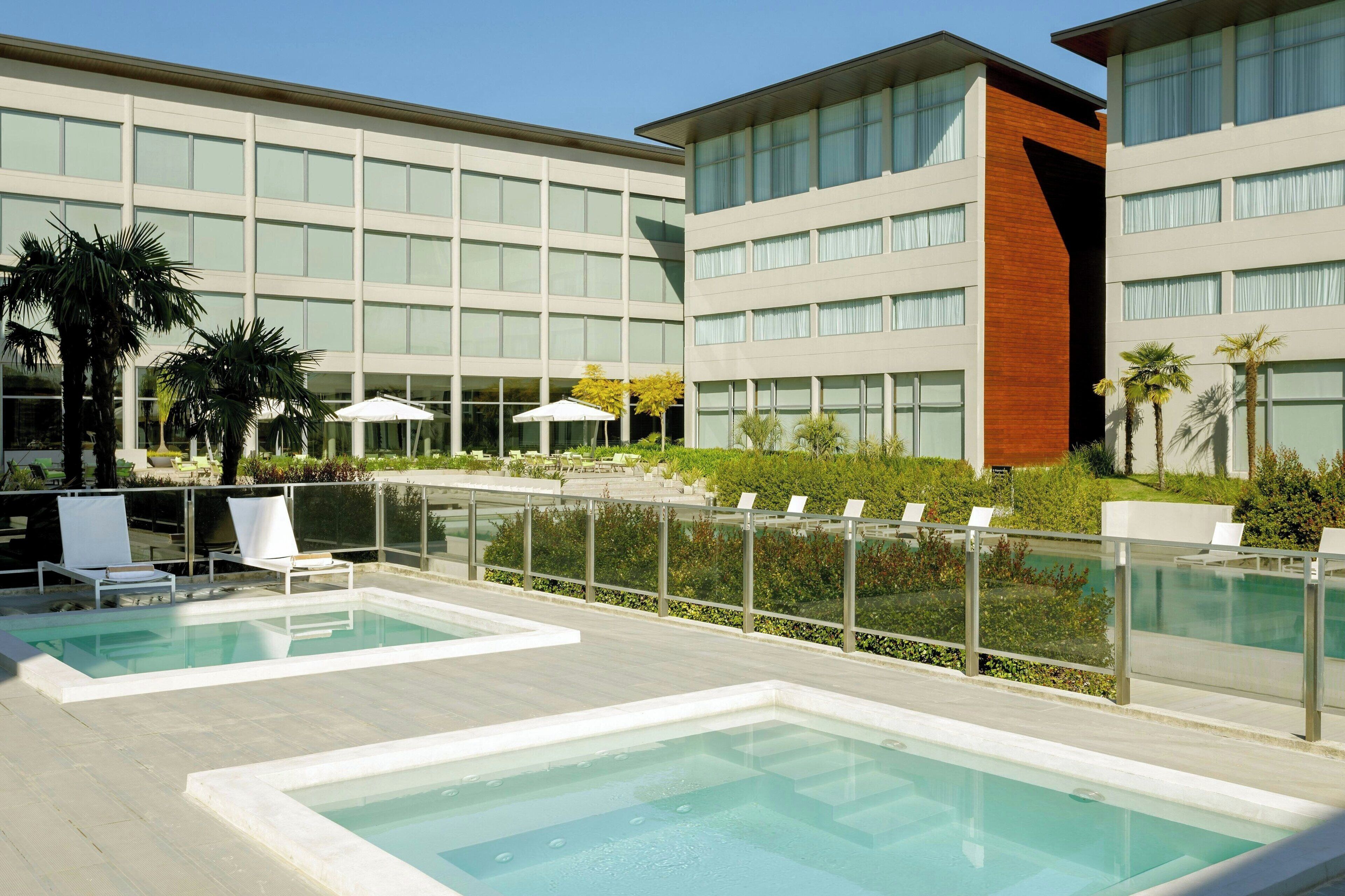 Um hotel moderno com área de piscina no terraço, incluindo espreguiçadeiras e guarda-sóis.
