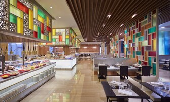Uma área de refeições moderna com buffet, assentos e um design de parede colorido.