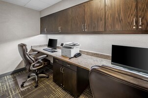 Um espaço de escritório moderno com mesa, cadeira, impressora e monitor de computador.
