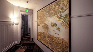 Um corredor com um mapa grande na parede, carpete estampado e um sinal de saída.