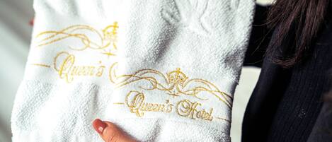 Toalha branca com bordado contendo a inscrição 'Queen's Hotel'.