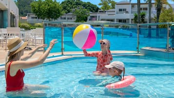 Área da piscina com vista clara, cadeiras de descanso e um edifício ao fundo.