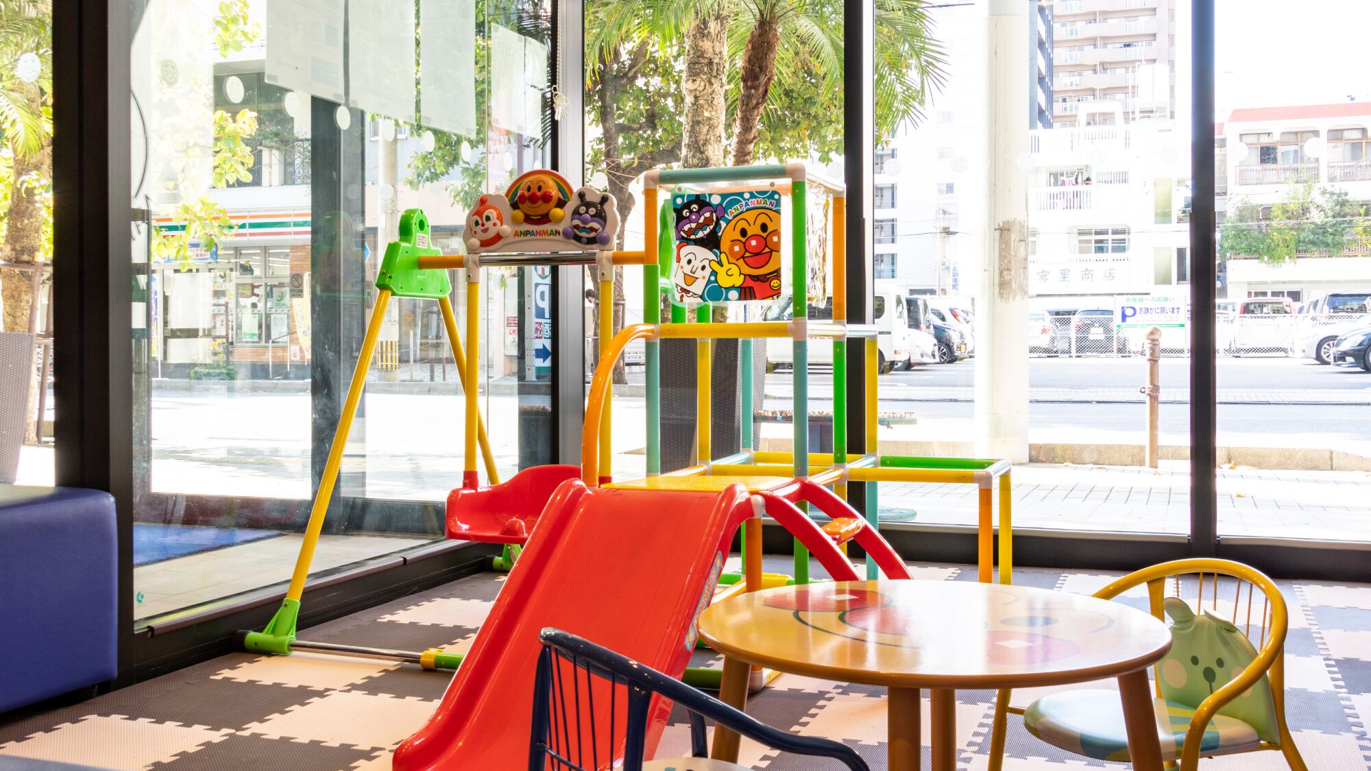 Uma área de recreação infantil com equipamentos coloridos, uma pequena mesa e cadeiras.