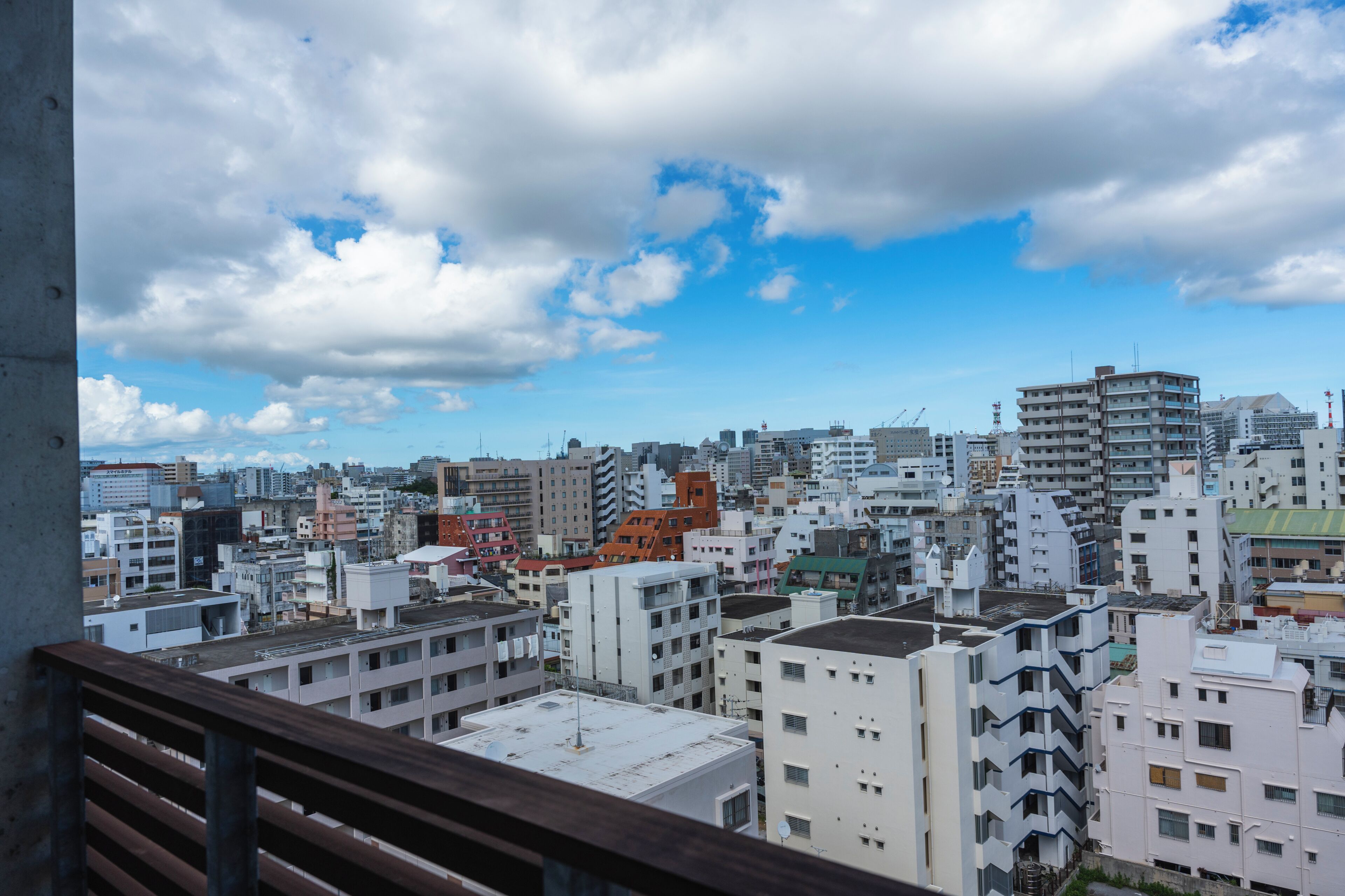 Vista urbana com diversos edifícios, incluindo construções residenciais e comerciais, vista de uma varanda.